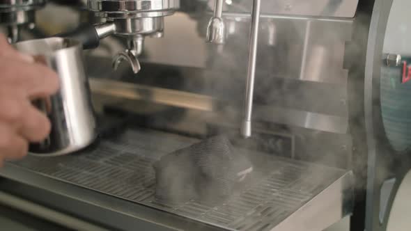 Slow mo close up of a puff of steam coming out of a cafe milk steamer ...