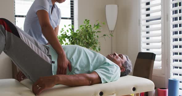 Mixed Race Female Physiotherapist Helping Senior Man Stretching His