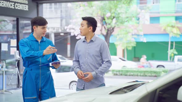 Asian automotive mechanic explain car condition to client in garage ...