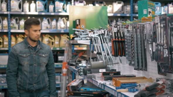 Smiling Young Man Purchasing a Hand Tool In Hardware Shop For His Car ...