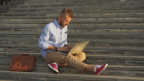 Handsome Student Sitting On Stone Steps And Using a Laptop, Stock Footage