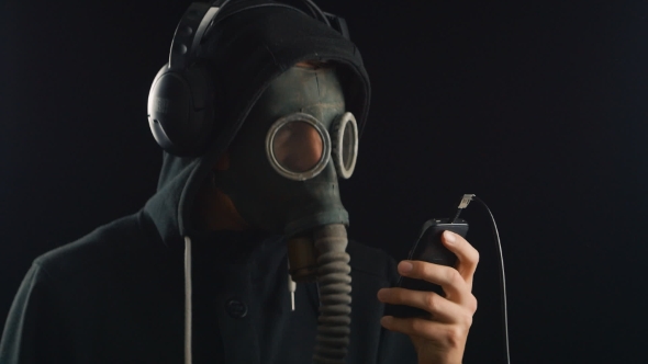 Man Listens To Music With Headphones With a Gas Mask Covering His Face ...