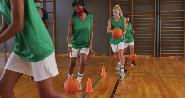 Diverse female basketball team and coach wearing face masks practice ...