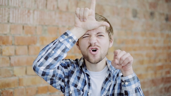 Cheerful Young Man Gesturing Loser Sign, Stock Footage | VideoHive