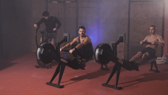 Front View Of Sportsmen Doing Cycling And Rowing Training At The Gym ...