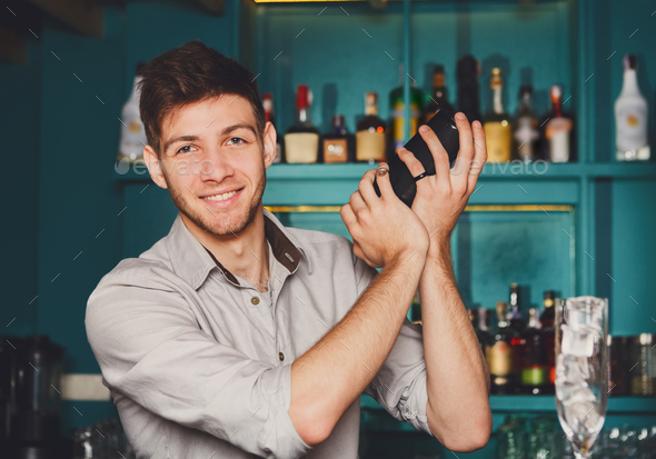 Young handsome barman in bar shaking and mixing alcohol cocktail Stock ...