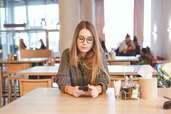 Portrait of cute freelancer girl sitting in a cafe. She wears brown ...