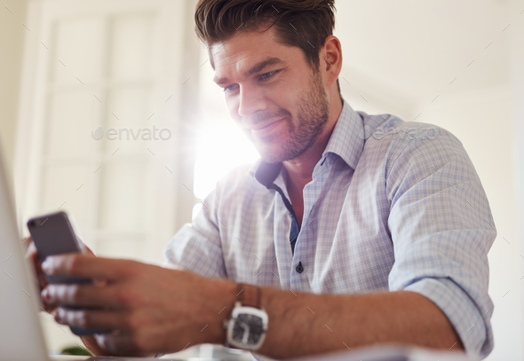 Handsome young man at home using mobile phone Stock Photo by jacoblund