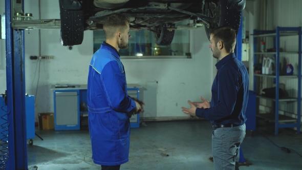 Auto Mechanic and Car Owner. Confident Auto Mechanic Explaining ...