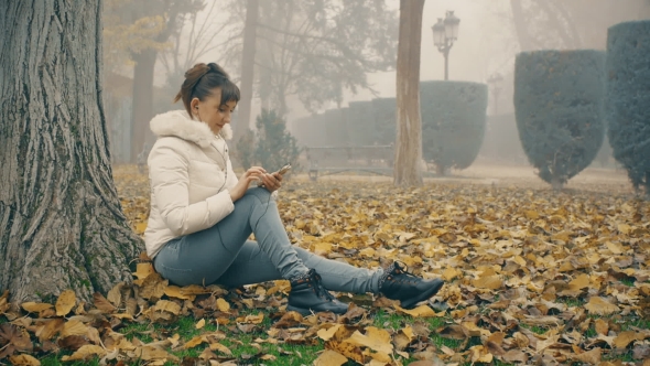 Woman Writing Message Sitting Under Tree on Fallen Leaves in Foggy ...