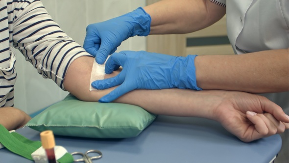 Nurse putting plaster on female arm after blood donation, Stock Footage