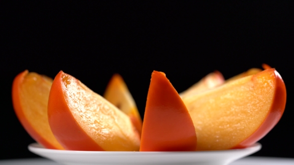 Persimmon Cut Into Slices Rotates on a Black Background, Stock Footage