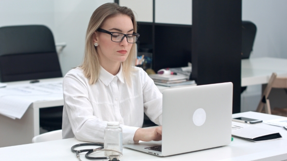 Concentrated Young Woman in Glasses Typing on the Laptop at Her Office ...
