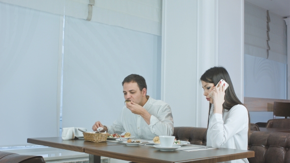 Young Man Eating While His Girlfriend Talking on the Phone at ...