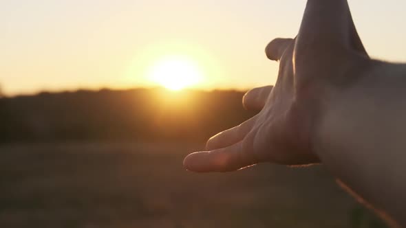 Male Hand Against Sunset. Touch the Sun. Sun Shines Through Fingers ...