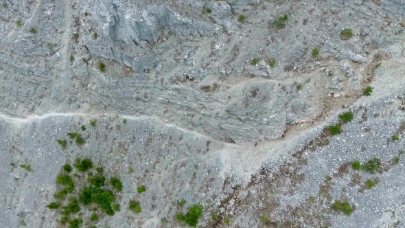 Aerial: Tilted Down While Moving Over Edge of Vertical Mountain Cliff ...