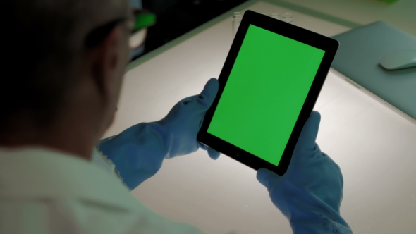 Scientist in Protective Rubber Gloves Is Using Tablet PC with Green ...