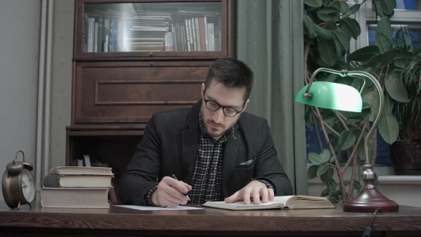 Concentrated Male Researcher Reading Book and Making Notes at the Desk ...