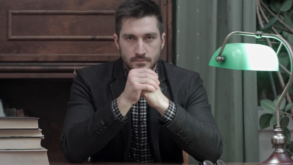 Serious Young Man Sitting at the Study Table with Books and Looking ...