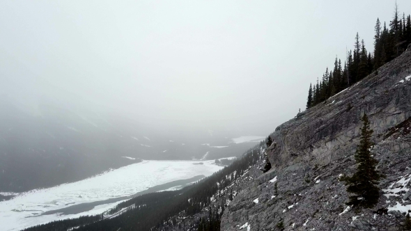 Aerial Flyby of Edge of Snowy Rocky Mountain During Snow Storm, Stock ...