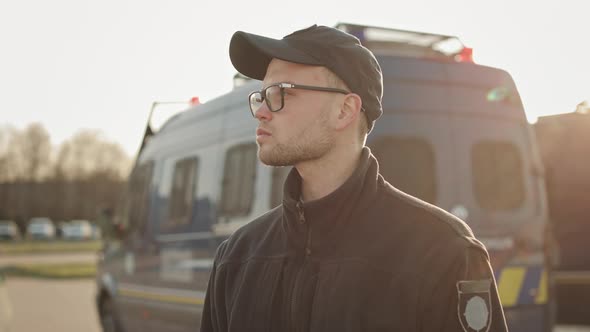 A Man in a Police Uniform is Standing Near Two Police Buses and Looking ...