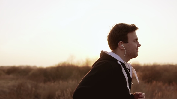 Lone Runner at Sunset Outdoors in Black Hooded Sweater., Stock Footage