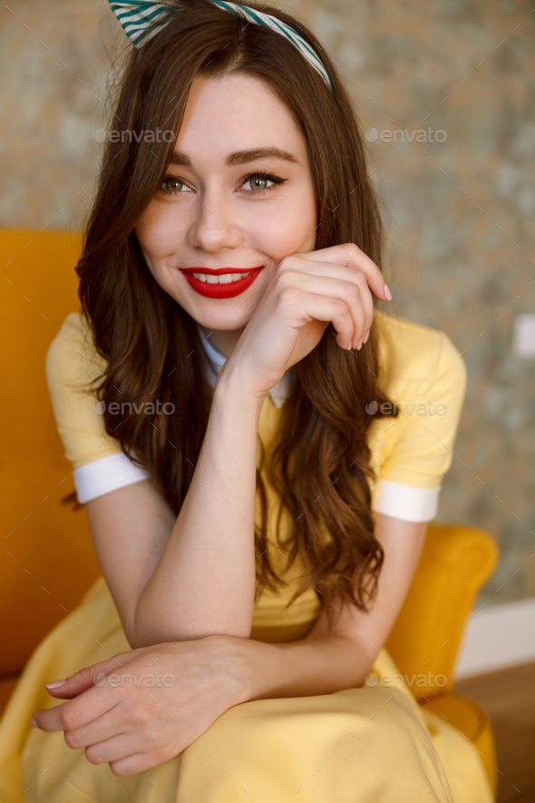 Cute pin up girl in yellow dress sitting in chair Stock Photo by ...