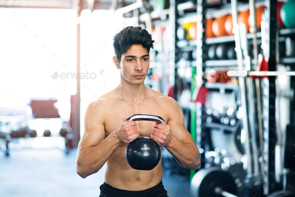Young fit hispanic man in gym exercising with kettlebell. Stock Photo ...