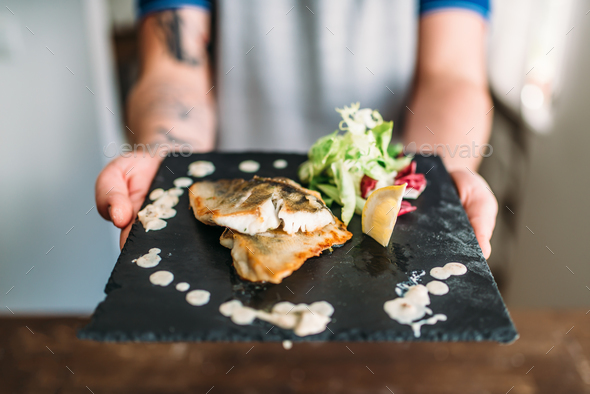 Male hands hold dish of fried fish fillet Stock Photo by NomadSoul1