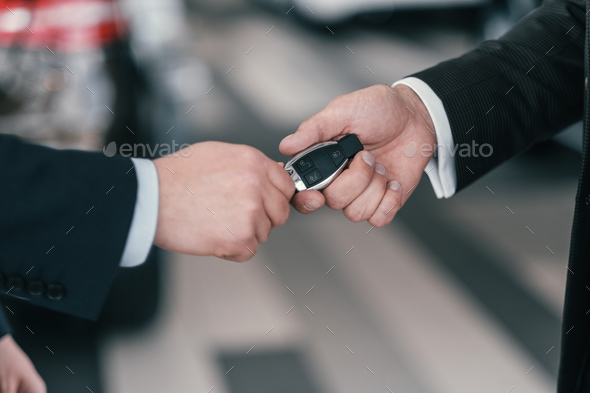 Giving a key from new car at dealership showroom Stock Photo by Nejron