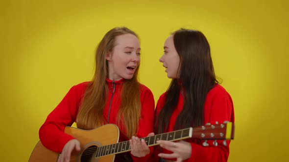 Happy Twins Singing Playing Guitar at Yellow Background Smiling, Stock ...