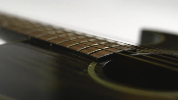Low sideways sliding view of an acoustic guitar. From the sound hole to ...