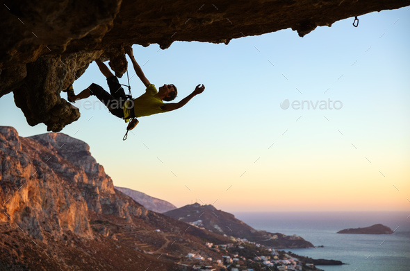 Young man climbing on roof in cave, view of coast below Stock Photo by ...