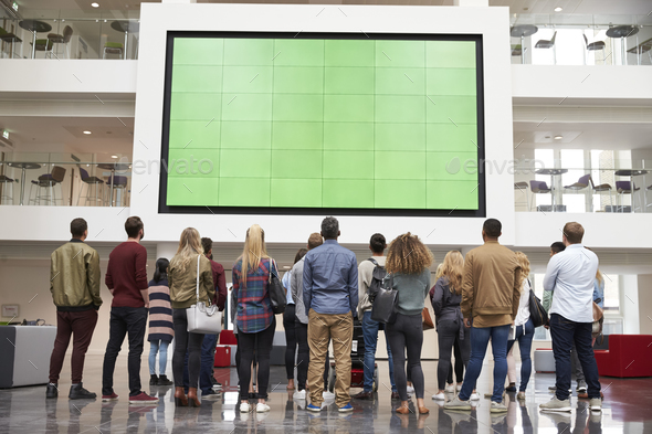 Students looking up at a big screen in university building Stock Photo ...