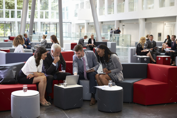 Businesspeople Meeting In Busy Lobby Of Modern Office Stock Photo by ...