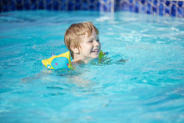 Happy blonde boy wearing floaties and swimming in pool Stock Photo by ...