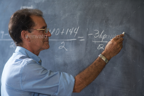Teacher Writing Math Formulas On Blackboard At High School Stock Photo ...