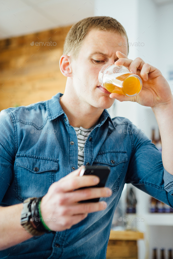 Man using phone while drinking beer Stock Photo by Click_and_Photo