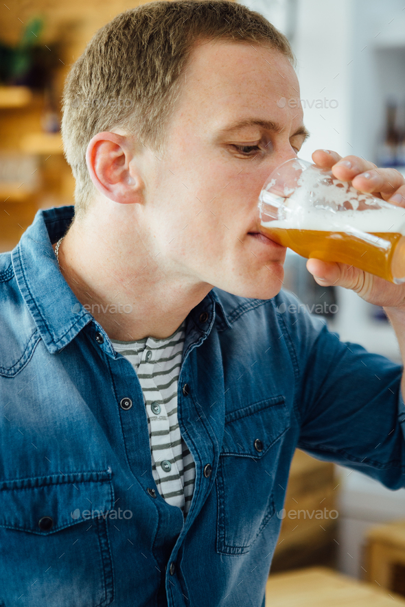 Handsome young man drinking light beer Stock Photo by Click_and_Photo
