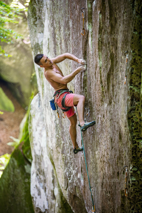 Rock climber on challenging route on vertical cliff Stock Photo by photobac