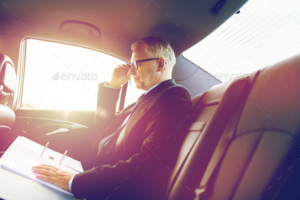 senior businessman with papers driving in car Stock Photo by dolgachov