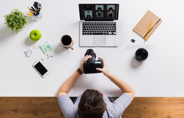 woman with camera and laptop at office table Stock Photo by dolgachov