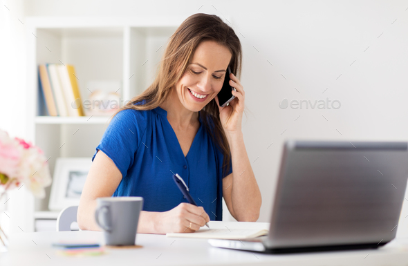 woman with notepad calling on smartphone at office Stock Photo by dolgachov