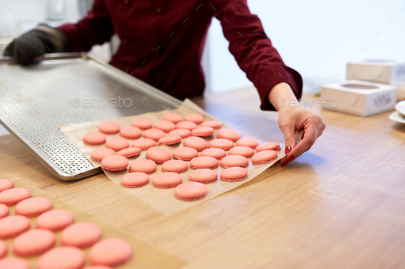 chef with macarons on oven tray at confectionery Stock Photo by dolgachov