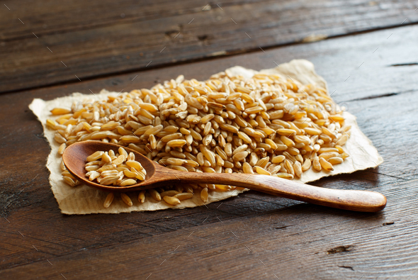 Pile of Kamut grain on wooden background Stock Photo by katrinshine