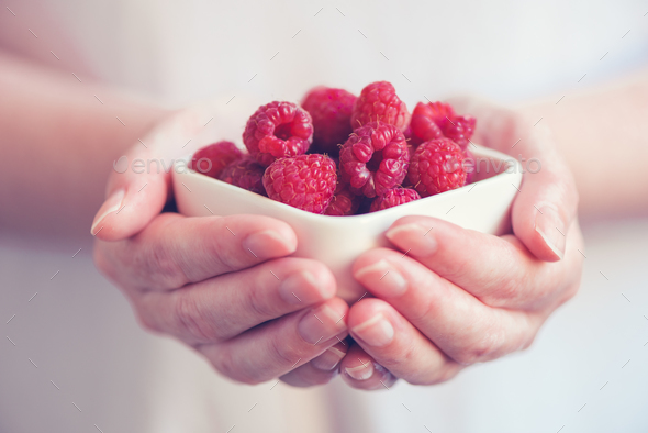 Crockery with raspberries in woman hands Stock Photo by stevanovicigor