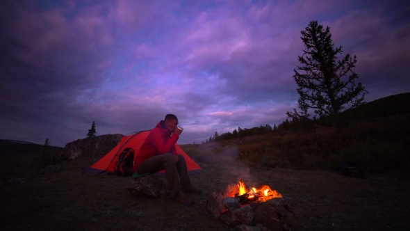Man Drinks at Camp Fire. Life on Travel, Evening Time, Stock Footage
