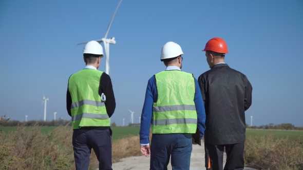Three Engineers Walking Against Wind Farm, Stock Footage | VideoHive