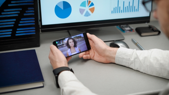 Manager at Work, Browsing Video on the Smartphone. Sitting in the ...