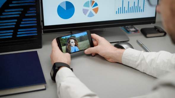 Manager at Work, Browsing Video on the Smartphone. Sitting in the ...